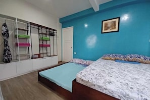 Quarto com uma cama, guarda-roupa e parede azul.