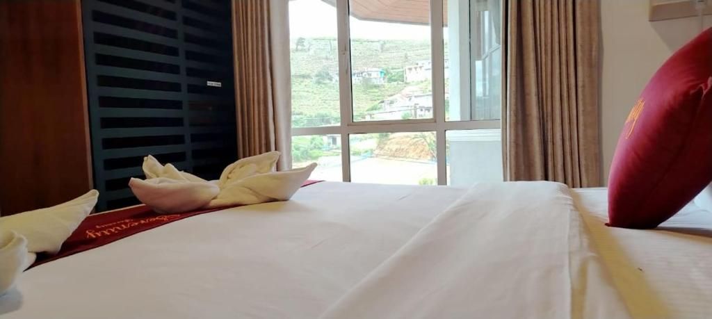 Quarto de hotel com cama, janela com cortinas e vista para o exterior.