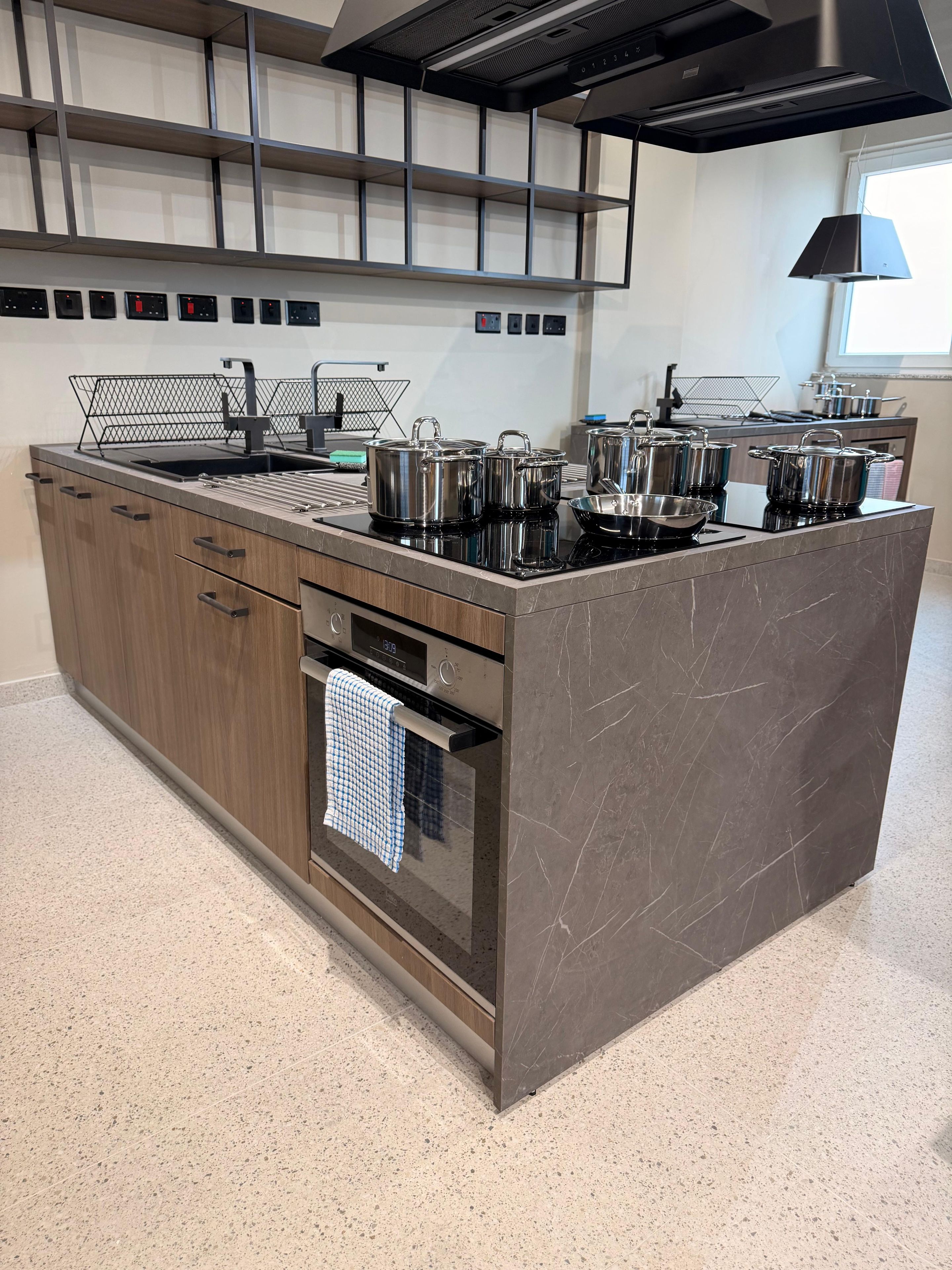 Cozinha moderna com ilha central, eletrodomésticos de aço inoxidável e forno embutido.