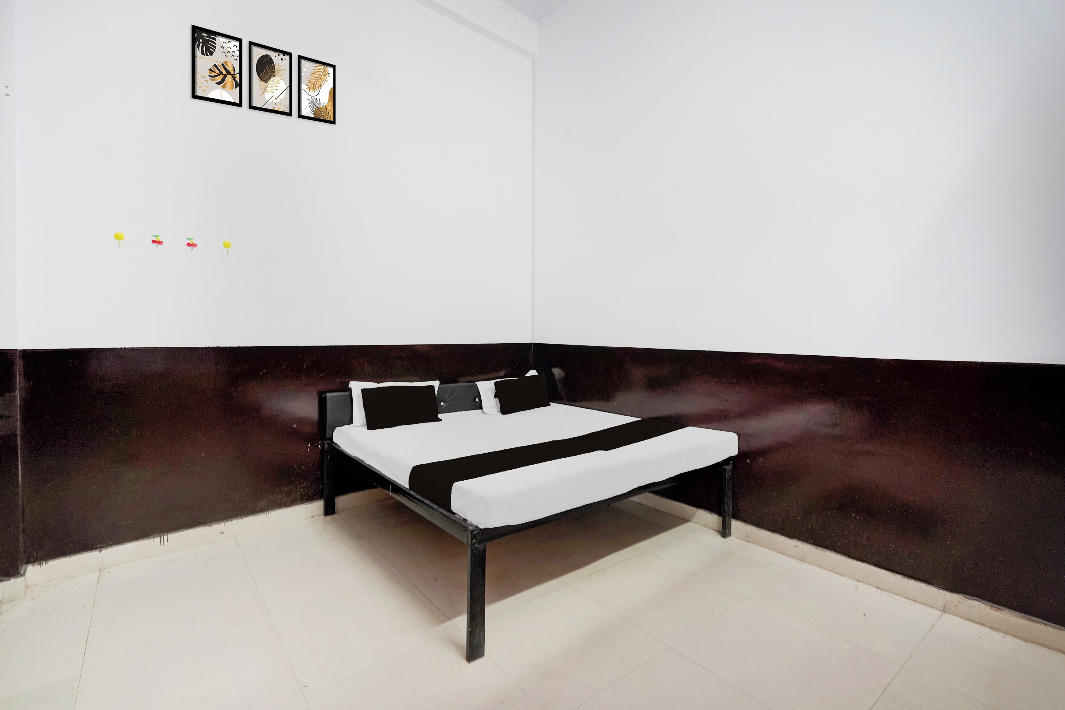 Quarto com cama, parede de destaque escura e três quadros na parede.