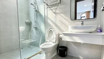 Um banheiro moderno com chuveiro envidraçado, vaso sanitário, pia e espelho.