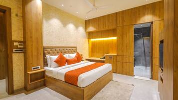 Quarto moderno com uma cama grande, painéis de madeira, ventilador de teto e banheiro com porta de vidro.