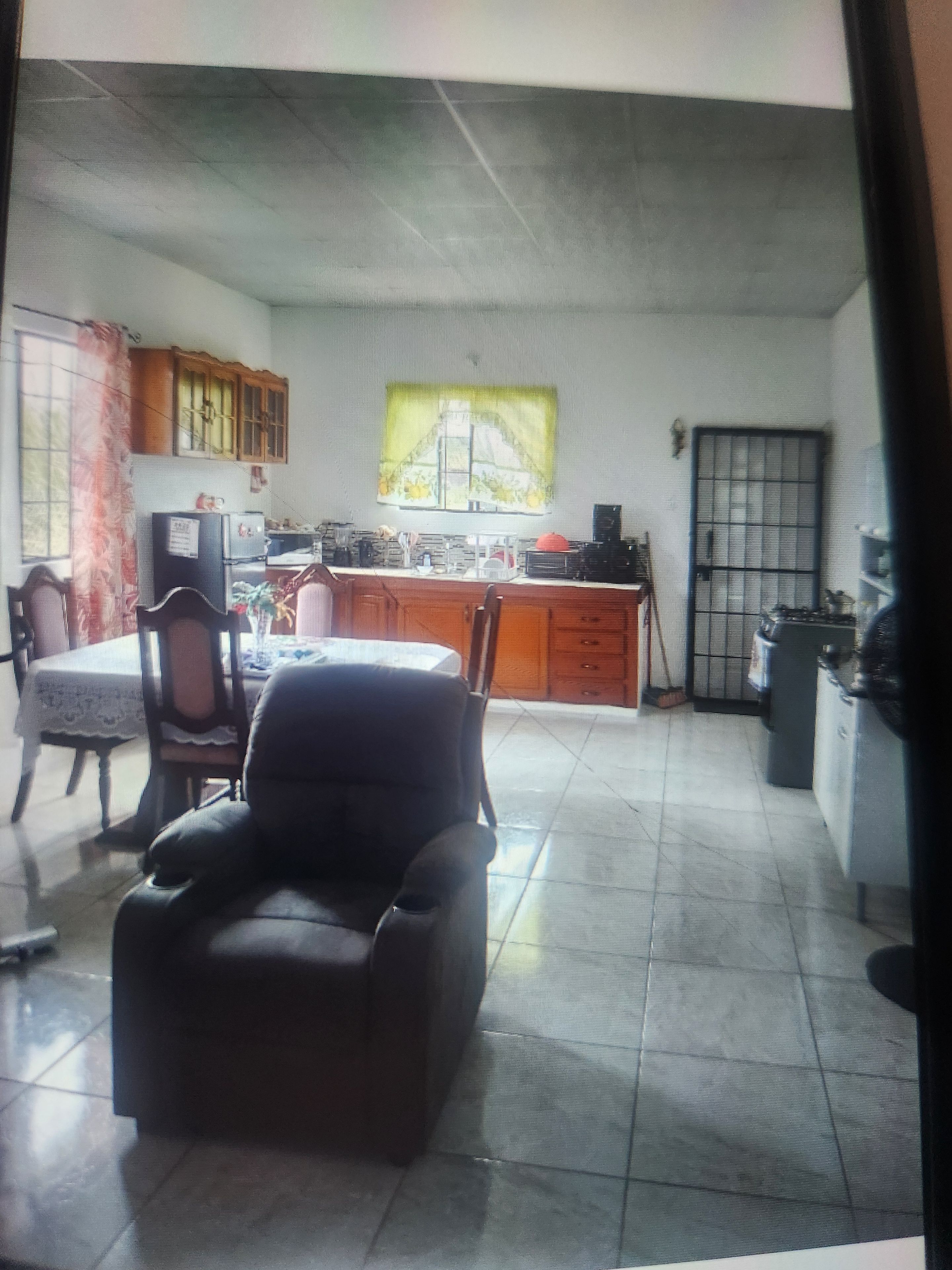 Sala de estar com sofá, mesa de jantar e cadeiras, cozinha com armários e janela com vista.