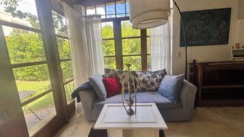 Sala de estar com sofá cinza, mesa de centro branca e um quadro na parede.
