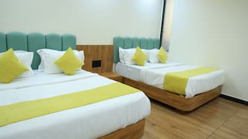Quarto de hotel com duas camas, cada uma com estrutura de madeira e roupa de cama branca, com almofadas amarelas e um corredor acolchoado amarelo.