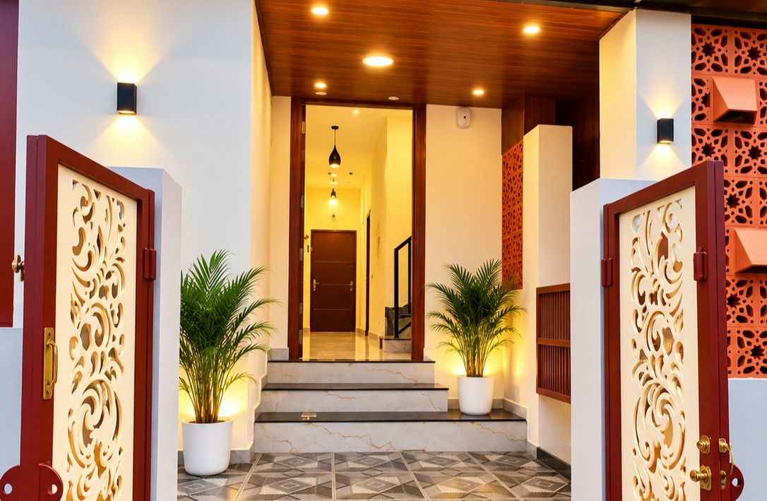 Entrada de hotel com escadaria para o interior, plantas em vasos e painéis decorativos na parede.