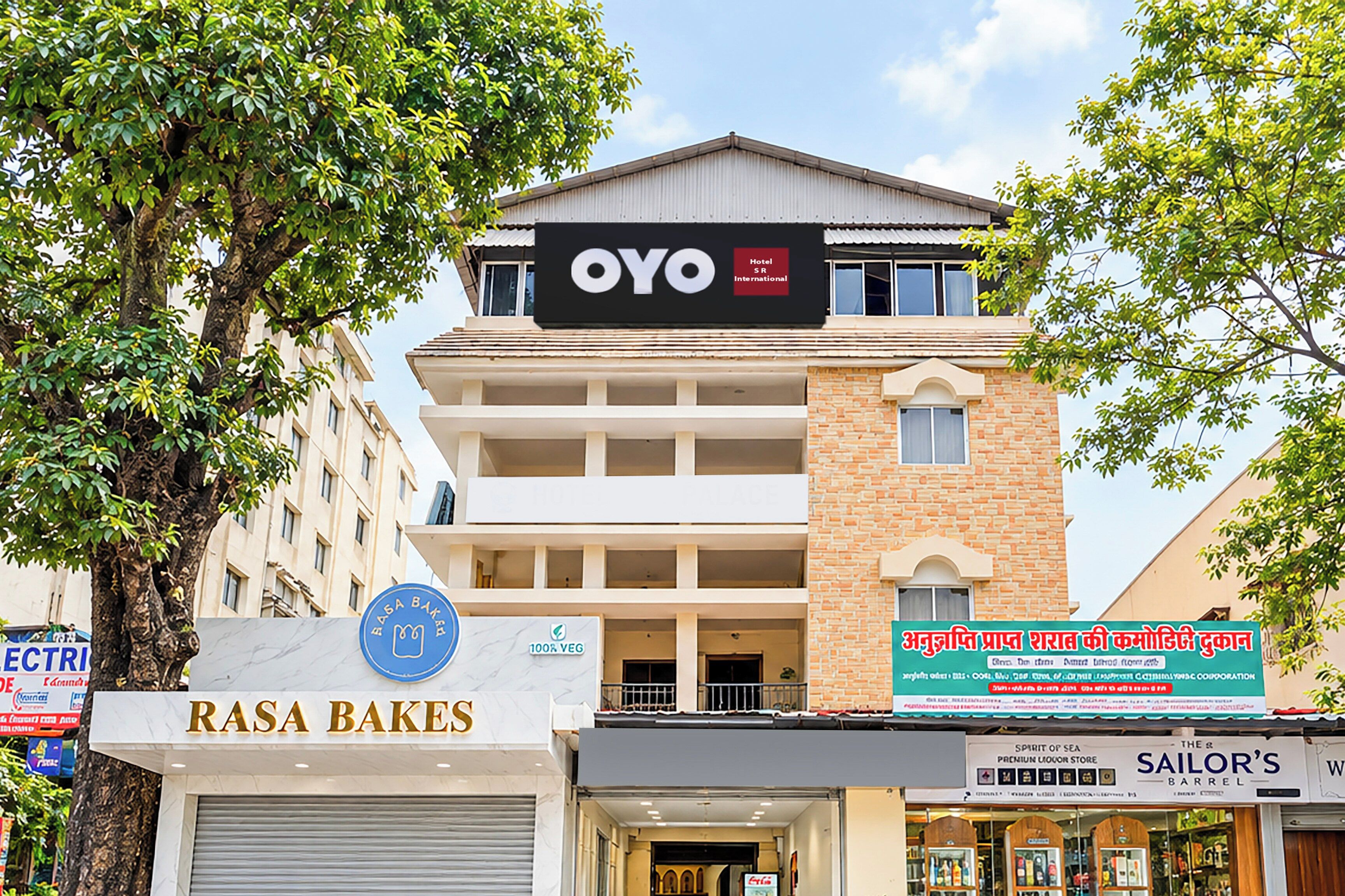 Um hotel com uma placa para OYO International, uma padaria chamada RASA BAKES e uma loja de bebidas com o nome Spirit of Sea.