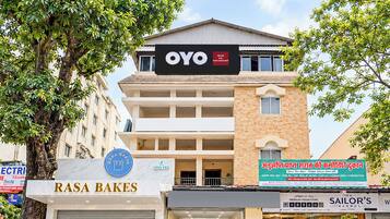 Um hotel com uma placa para OYO International, uma padaria chamada RASA BAKES e uma loja de bebidas com o nome Spirit of Sea.