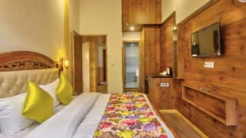 Quarto com cama, televisão fixada na parede e cabeceira de madeira.