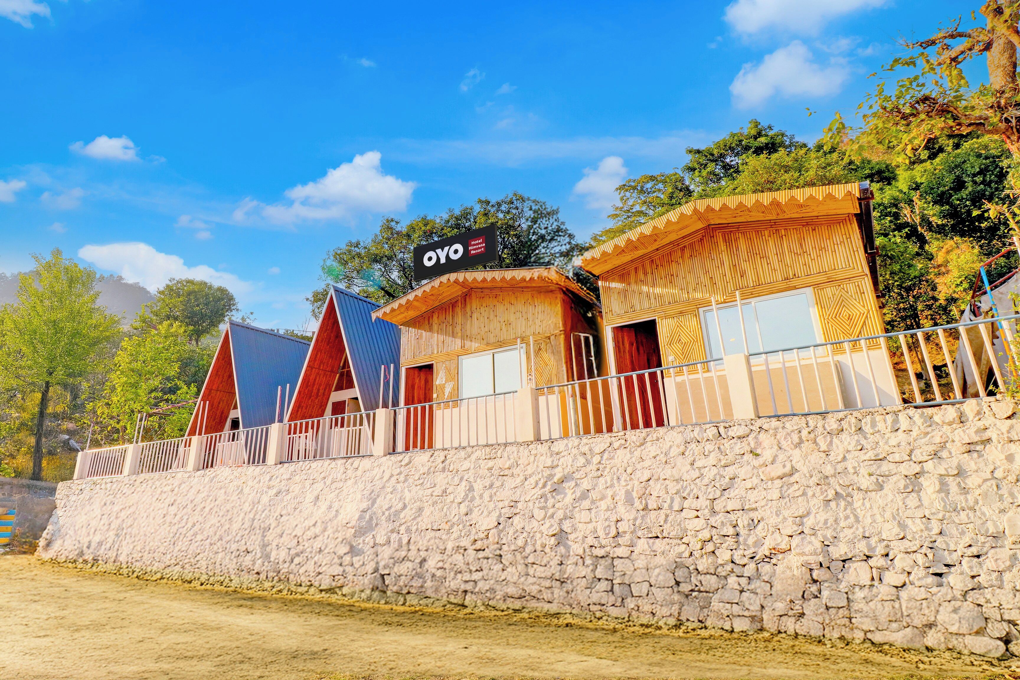 Um hotel com parede de pedra e várias cabanas de madeira.