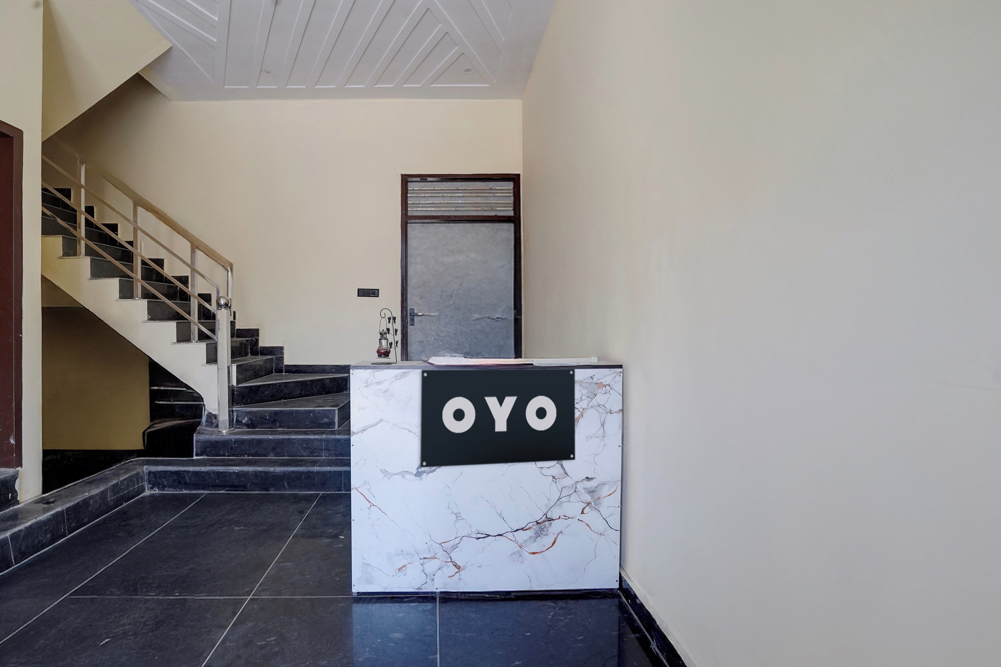 Uma mesa de recepção com tampo de mármore e uma placa com a inscrição 'OYO'.