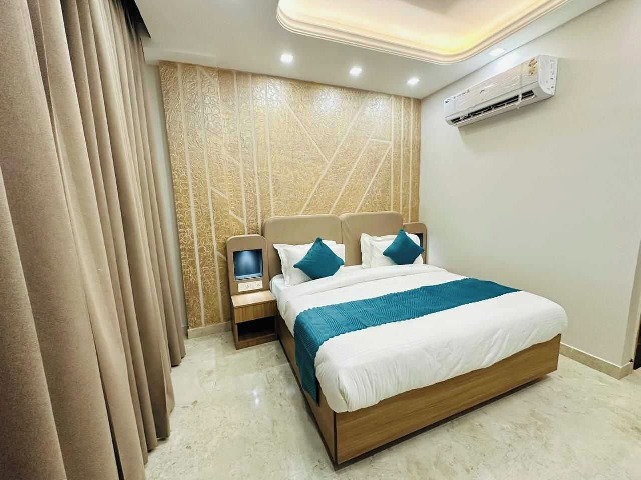 Quarto de hotel com uma cama grande, mesas de cabeceira, ar condicionado e televisão em um suporte.