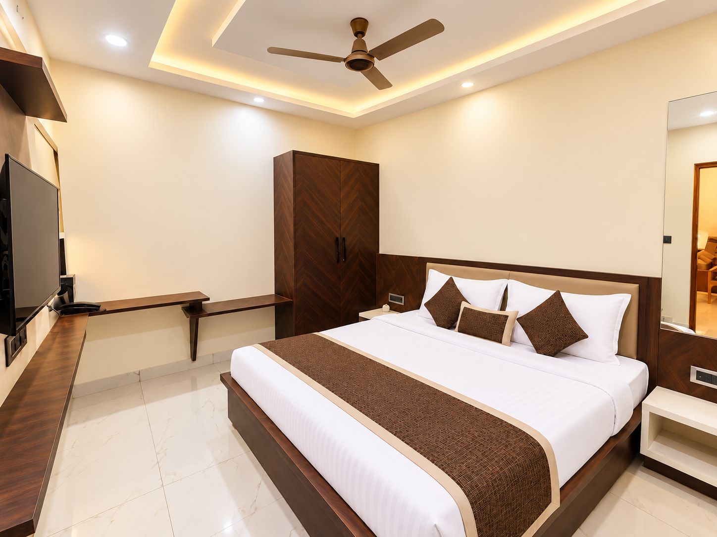 Quarto de hotel com cama grande, armário, televisão e ventoinha no teto.
