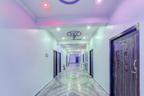 Corredor de hotel com piso de mármore, iluminação no teto e ventilador de teto.