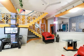 Um interior moderno com escada, poltrona vermelha, mesa de vidro e balcão de recepção.