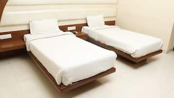 Duas camas de solteiro com estrutura de madeira e roupa de cama branca em um quarto de hotel.