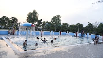 Piscina com fonte, cercada por um muro baixo e árvores.