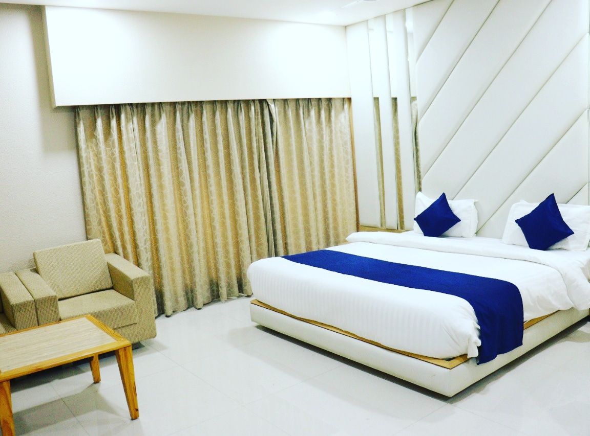 Quarto de hotel com uma cama grande, um sofá e uma mesinha.