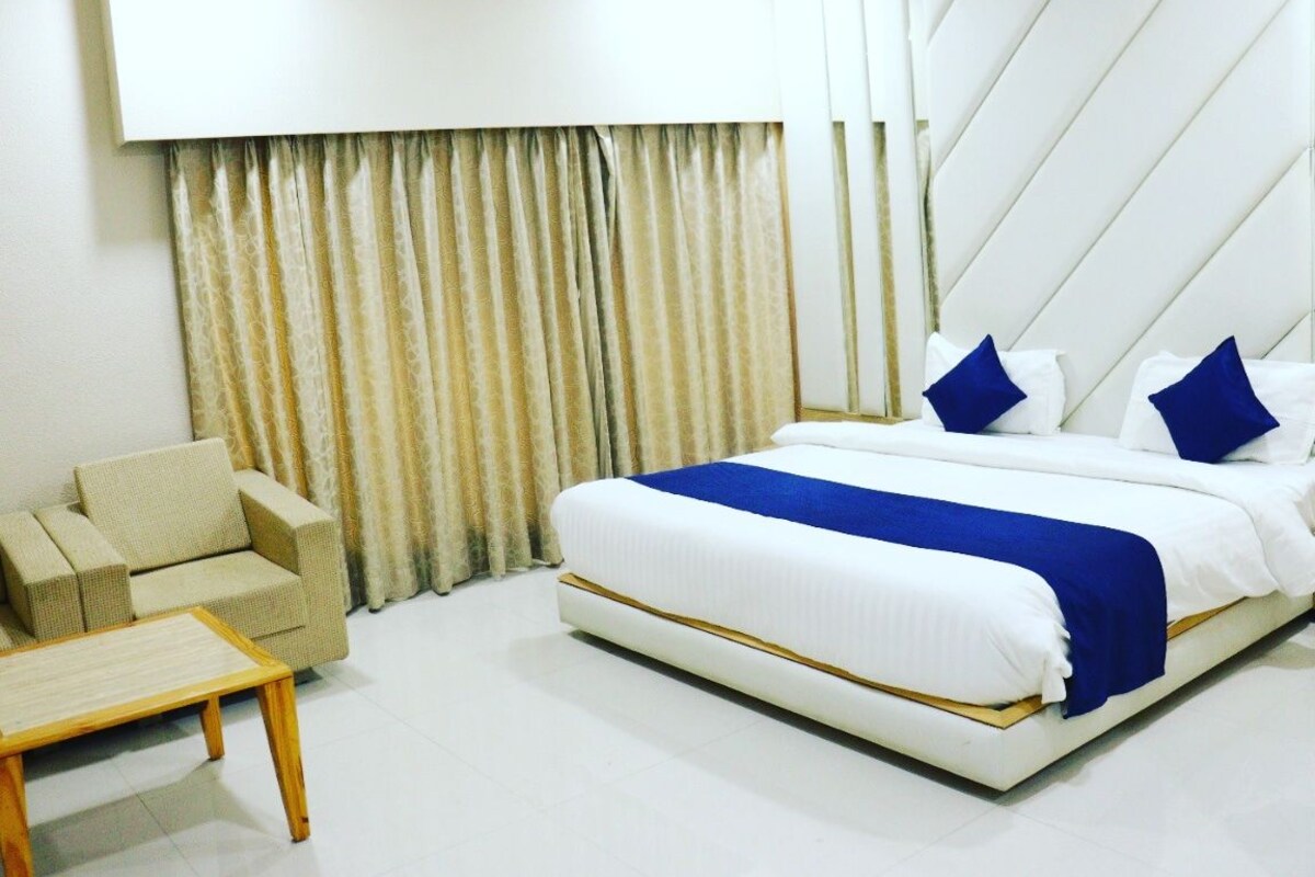 Quarto de hotel com uma cama grande, um sofá e uma mesinha.