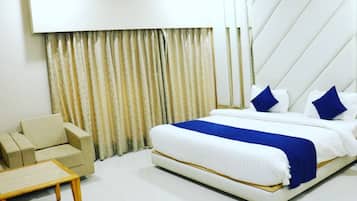 Quarto de hotel com uma cama grande, um sofá e uma mesinha.