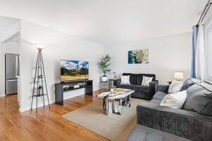 Uma sala de estar moderna com televisão de tela plana, sofá, mesa de centro e luminária de chão.