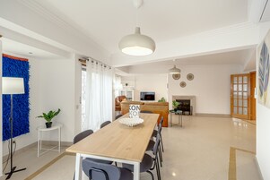 Uma sala de estar moderna com área de jantar, lareira e televisão.