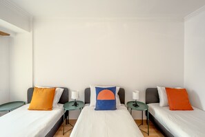 Quarto de hotel com duas camas de solteiro, cada uma com travesseiro e mesa de cabeceira.