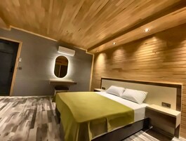 Quarto com cama, mesas de cabeceira, espelho e teto de madeira.