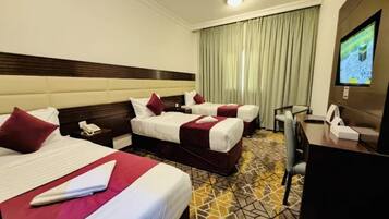 Quarto de hotel com duas camas, uma escrivaninha, televisão e carpete estampado.