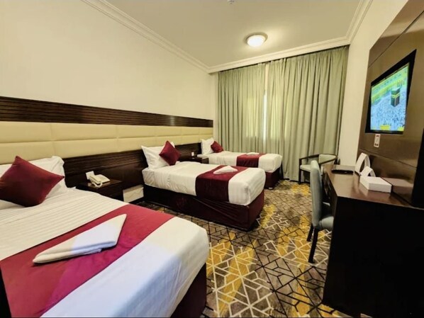 Quarto de hotel com duas camas, uma escrivaninha, televisão e carpete estampado.