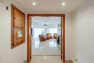 Ampla sala de estar com porta de madeira, lareira e disposição de assentos.