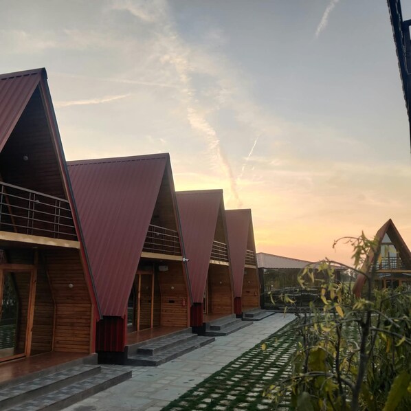 Uma fileira de edifícios modernos com telhados triangulares e um caminho que leva a uma porta de madeira.