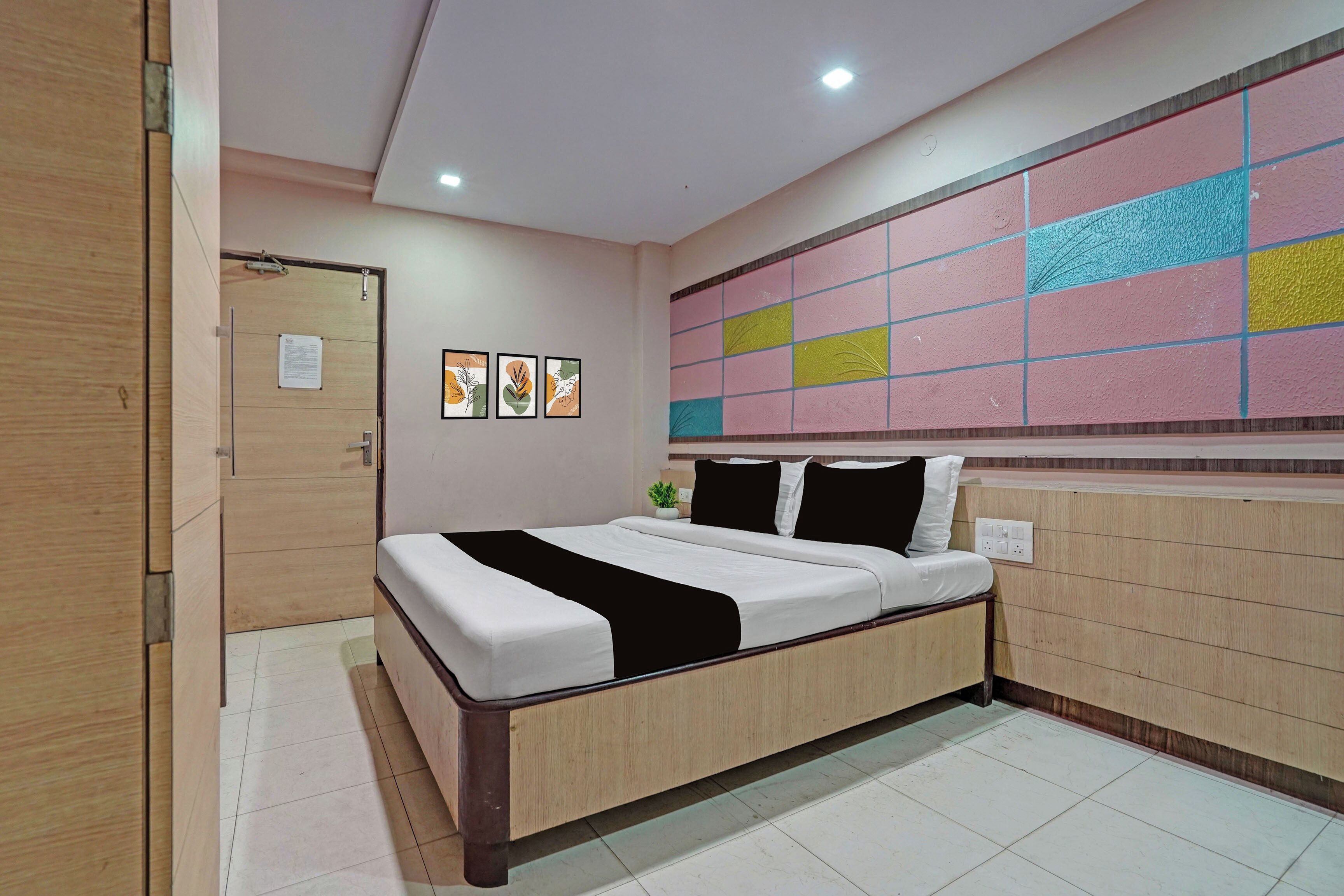 Quarto com cama, guarda-roupa de madeira, porta e parede com design de painel colorido.