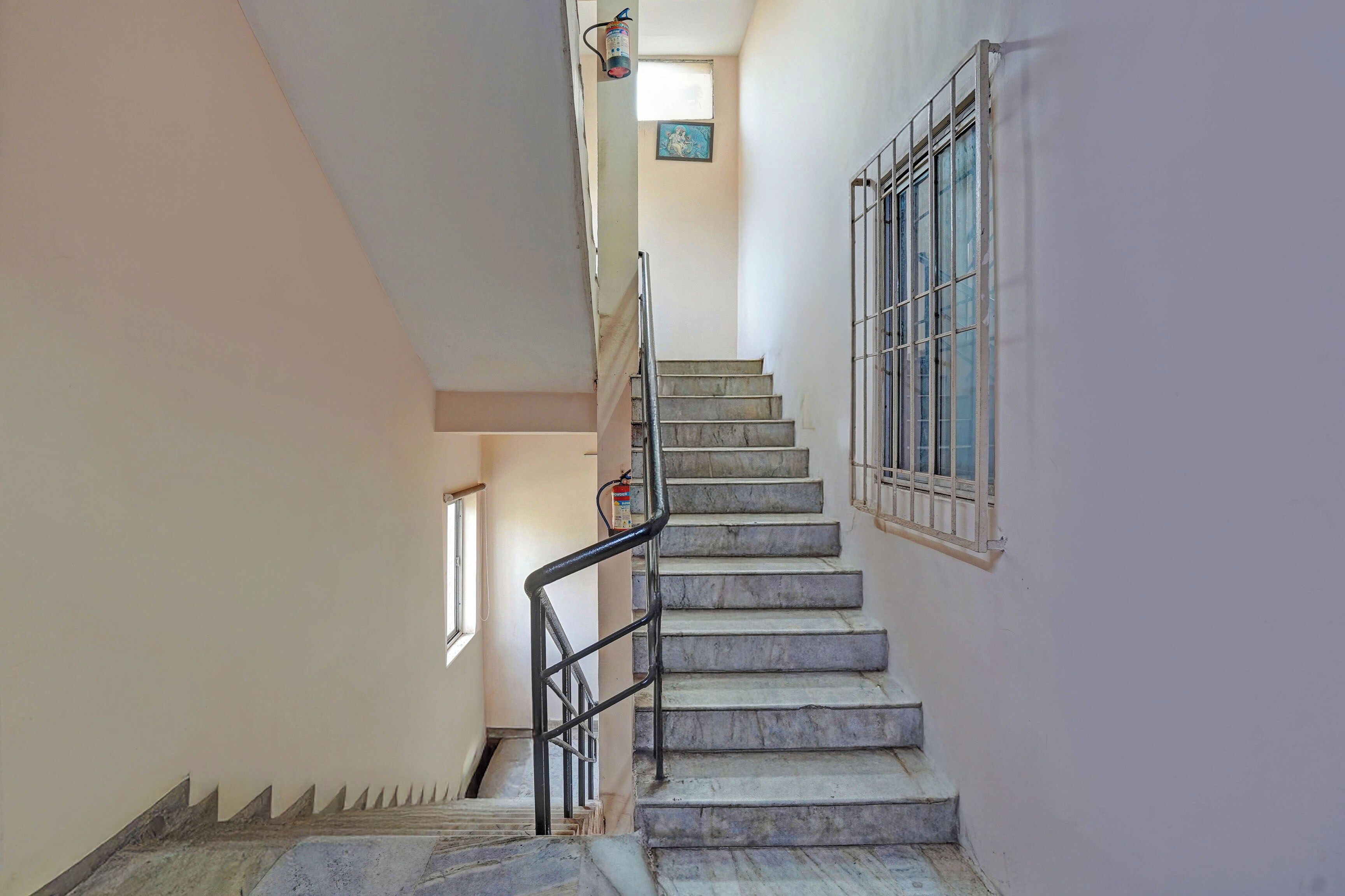 Uma escadaria com grades de metal que leva a um patamar com janela.