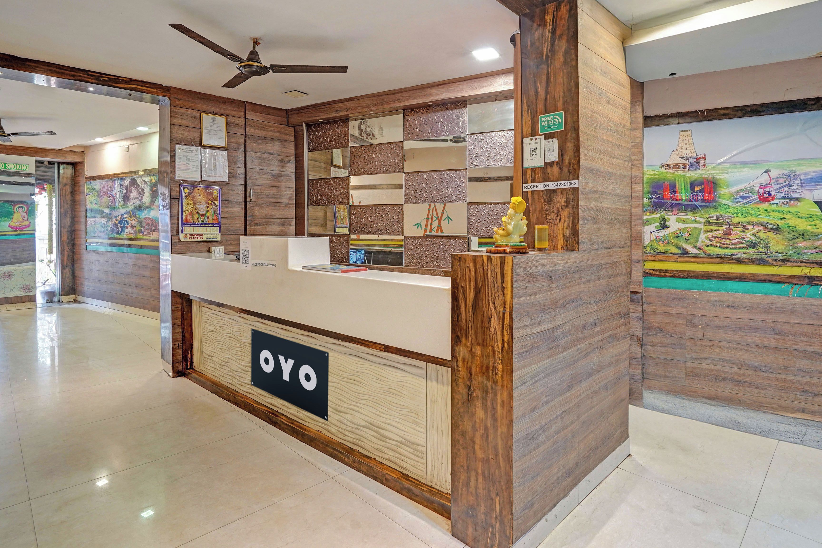 Uma receção com uma placa a indicar 'OYO' num hall de hotel com lambris e um mural na parede.
