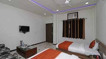 Quarto de hotel com duas camas, televisão, escrivaninha e ventoinha no teto.