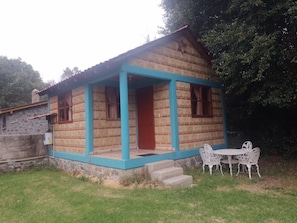 Um pequeno edifício térreo com varanda, janela e porta.
