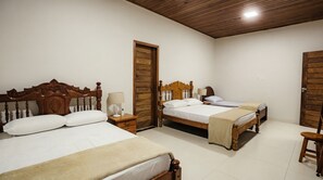 Quarto de hotel com duas camas de madeira, um guarda-roupa de madeira e uma cadeira de madeira.