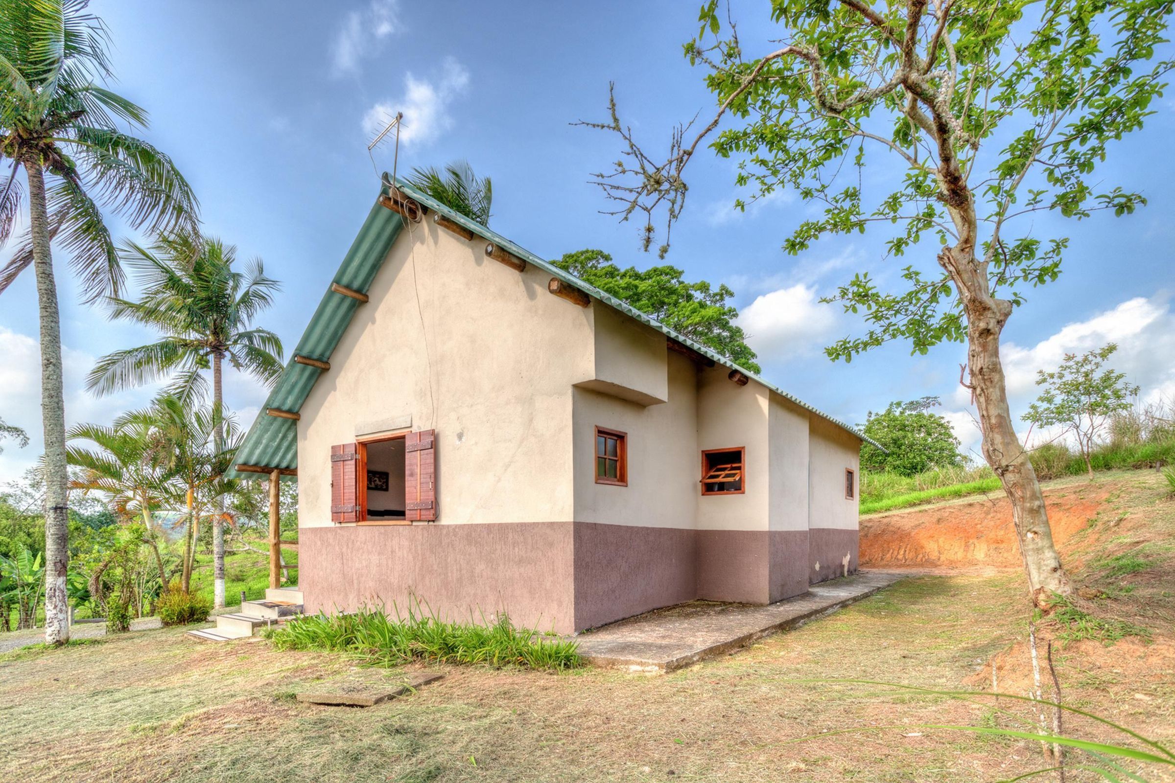 Uma casa térrea com telhado inclinado, duas janelas e um pequeno alpendre.