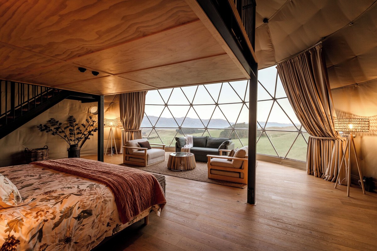 Um quarto espaçoso com uma cama grande, um espaço para sentar com vista para o exterior e uma escadaria.