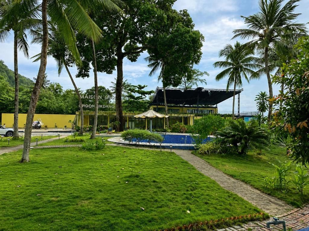 Hotel com piscina, rodeado por vegetação exuberante e palmeiras.