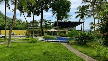 Hotel com piscina, rodeado por vegetação exuberante e palmeiras.