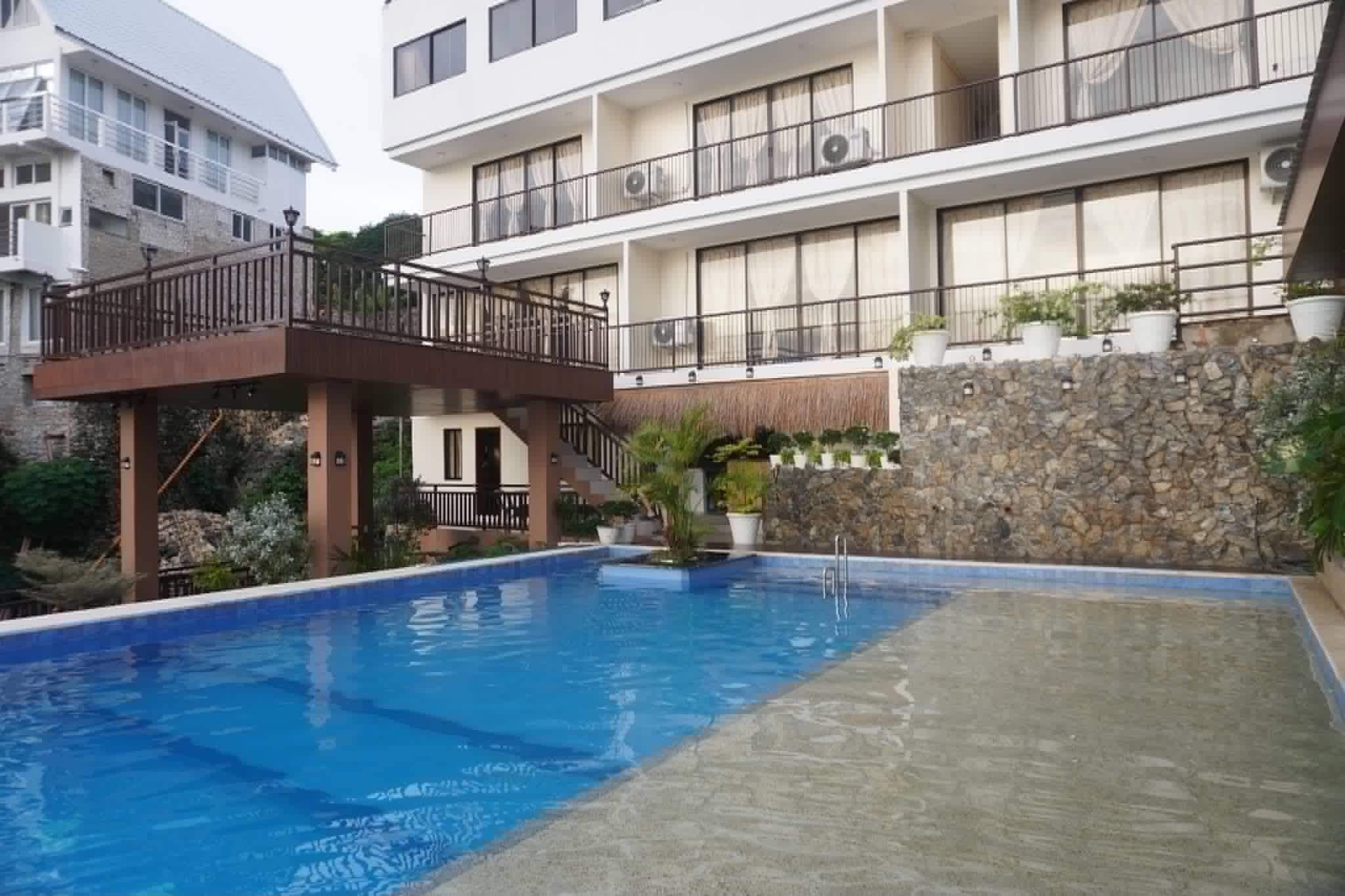 Piscina com deck de madeira e parede de pedra.