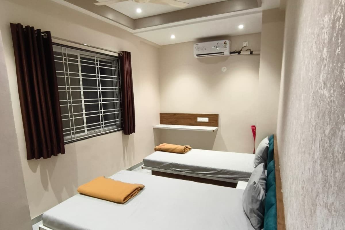 Quarto de hotel com cama, ar condicionado, janela com cortinas e ventilador de teto.