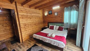 Quarto com painéis de madeira, uma cama, um criado-mudo e uma porta.
