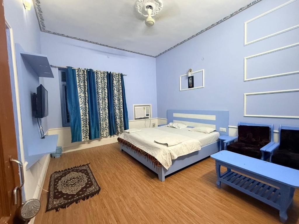 Quarto com cama, mesa de cabeceira e uma pequena mesa com cadeiras.