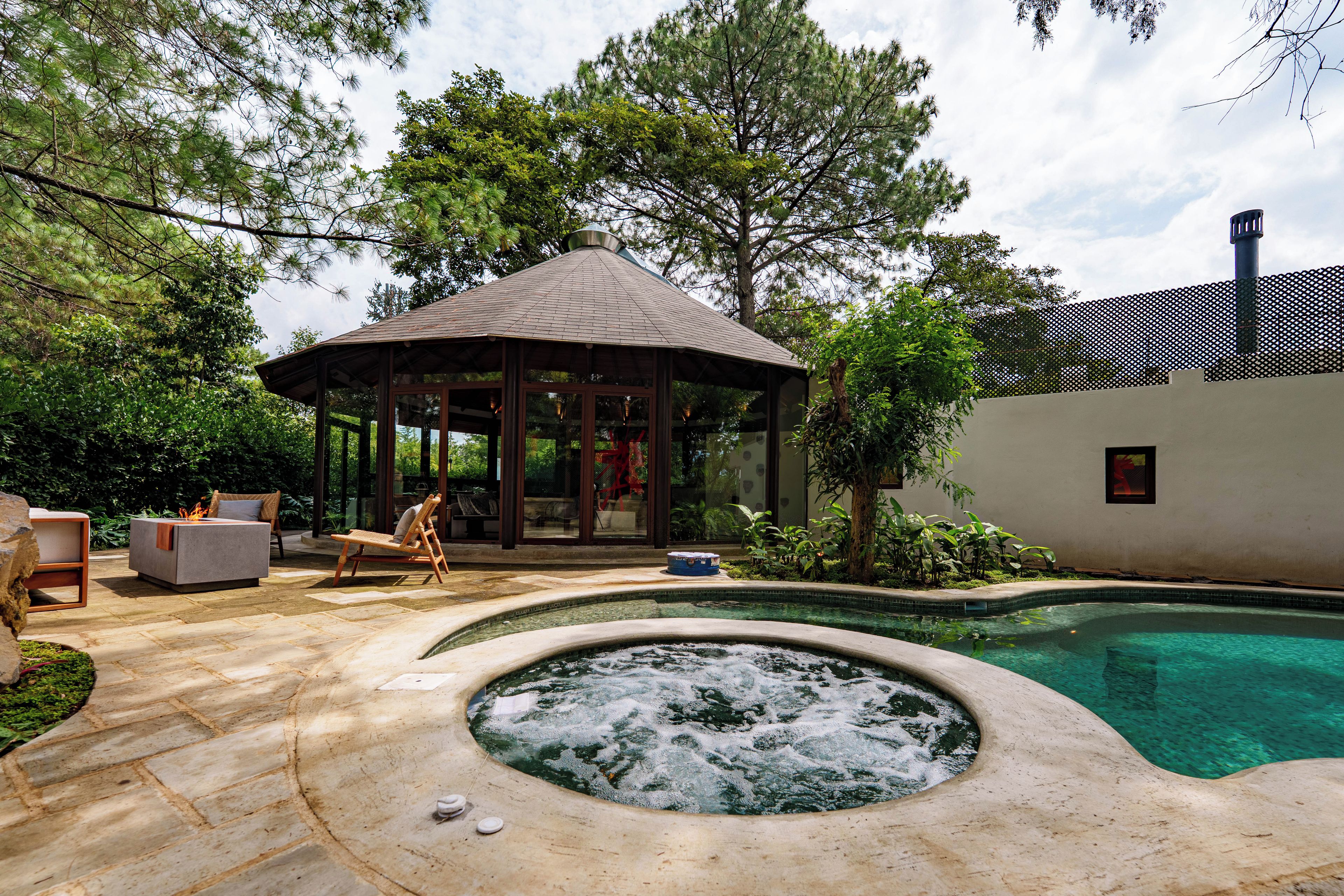 Um quintal com hidromassagem, um gazebo e uma piscina.