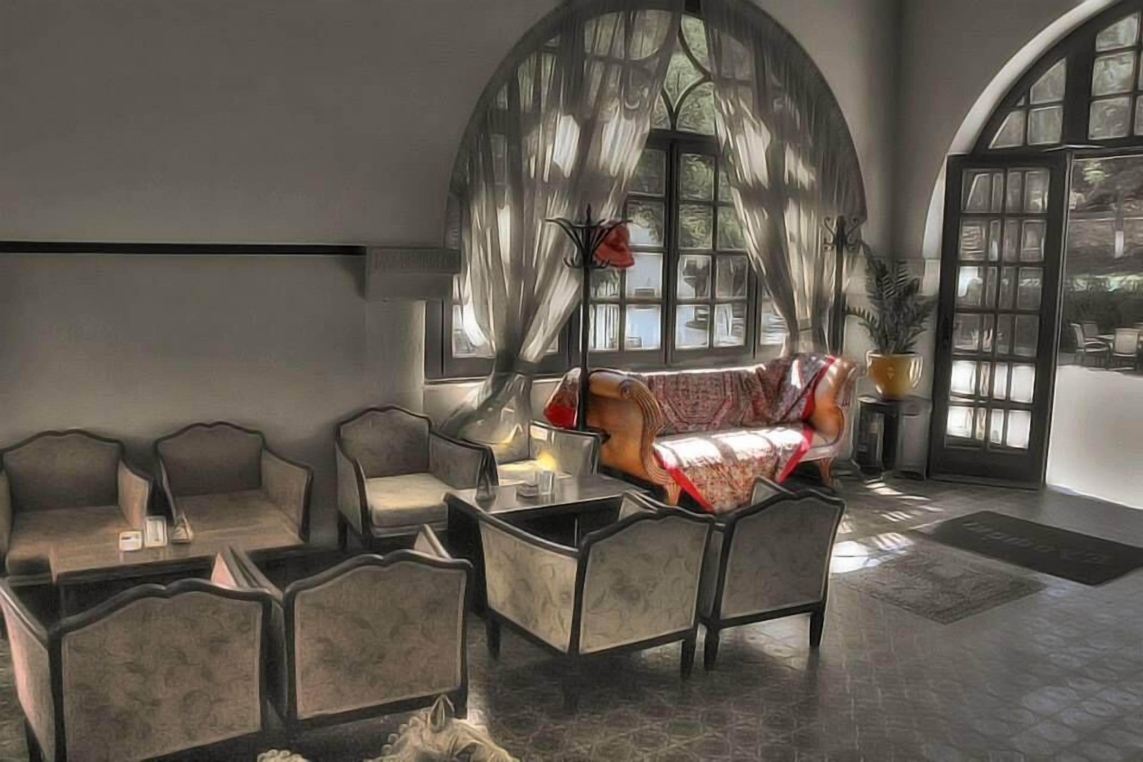 Uma área de estar moderna com uma grande janela em arco, assentos confortáveis e uma planta decorativa.