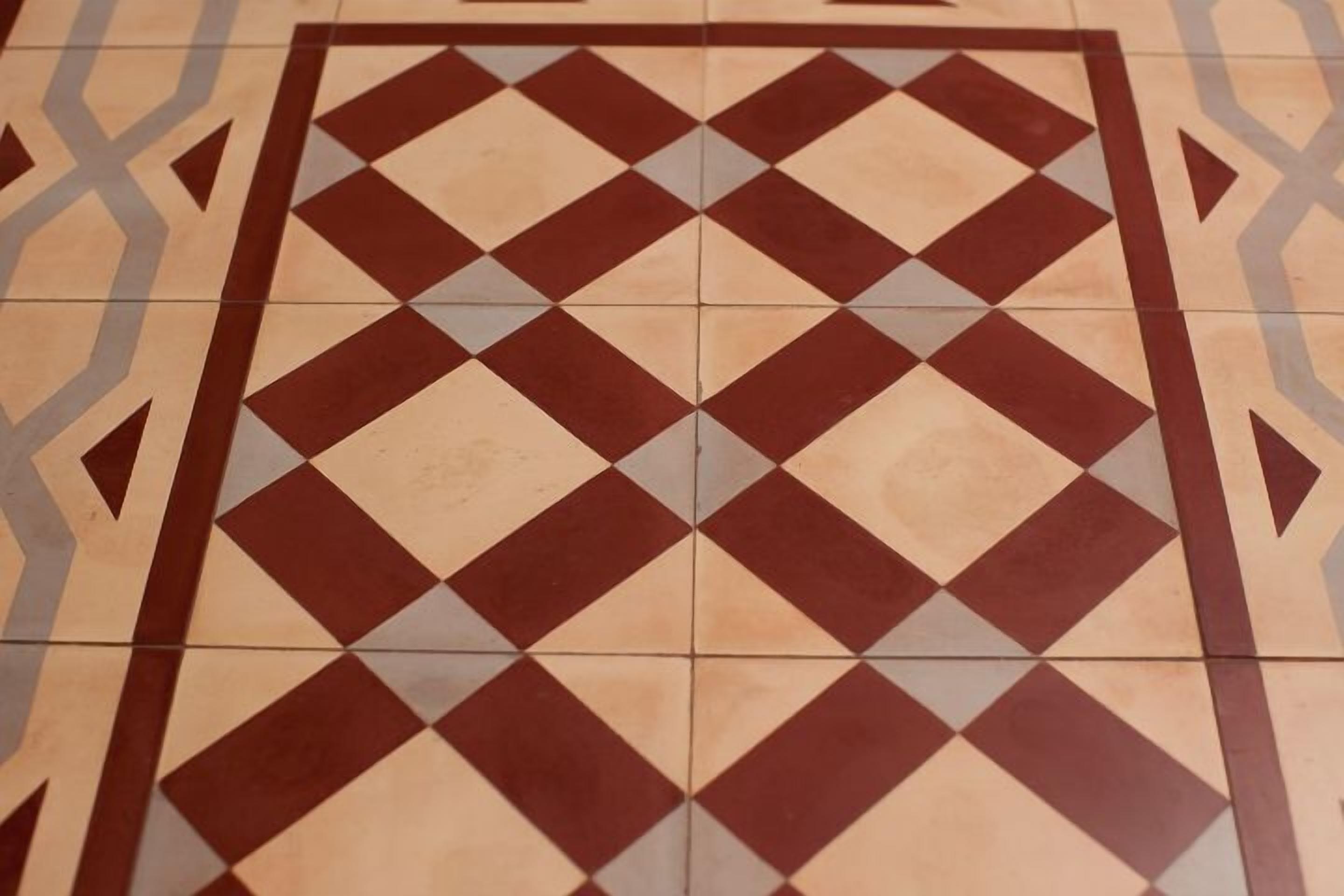 Piso com padrão geométrico de azulejos claros e escuros alternados.