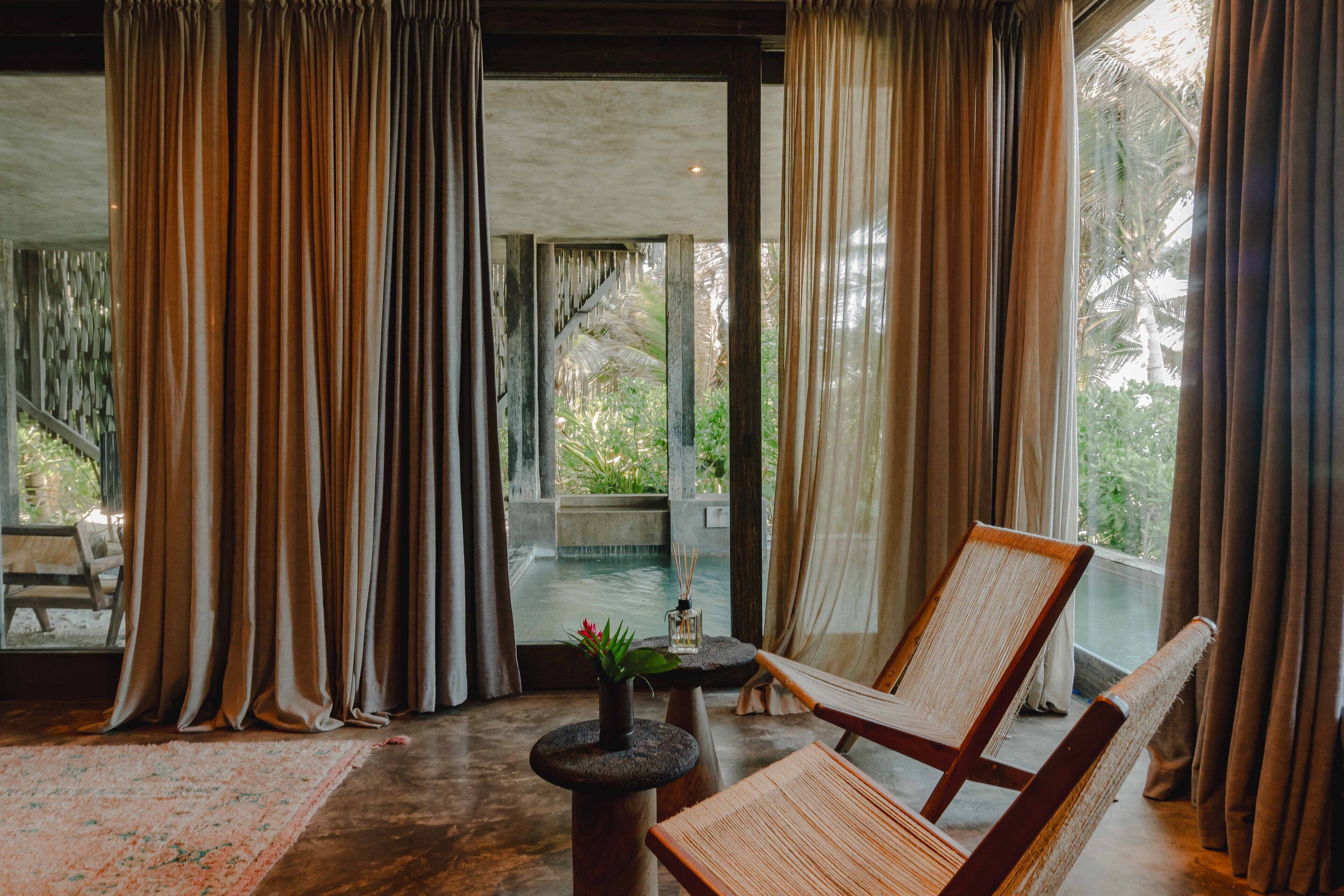 Quarto com vista para uma piscina, uma cadeira de rede e uma pequena mesa com uma planta.